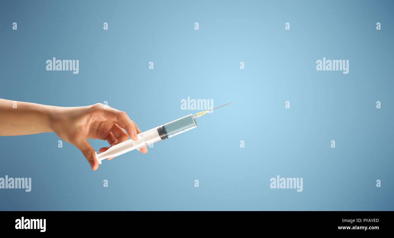 Female doctor hand holding syringe with blue background Stock Photo - Alamy