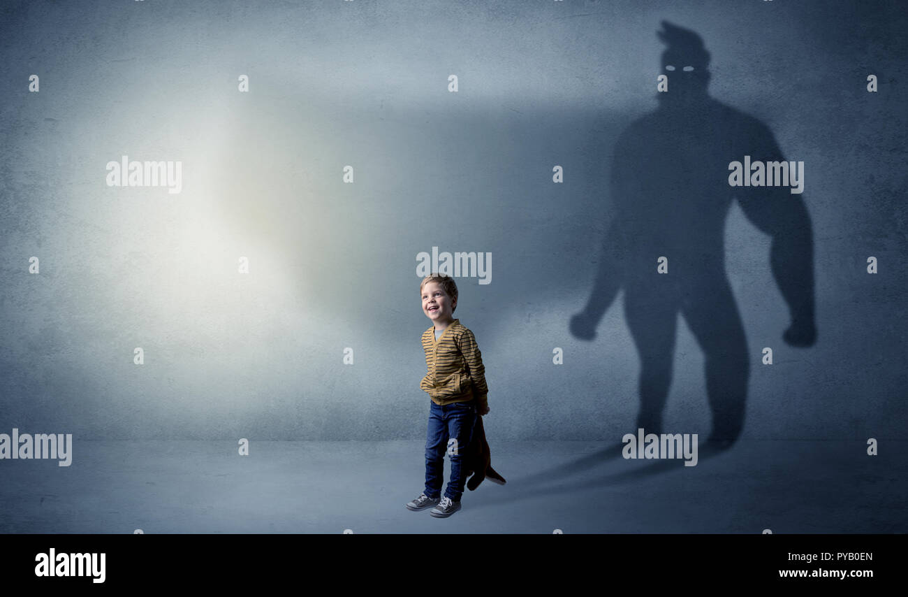 Cute kid in a room with plush on his hand and hero shadow on his ...