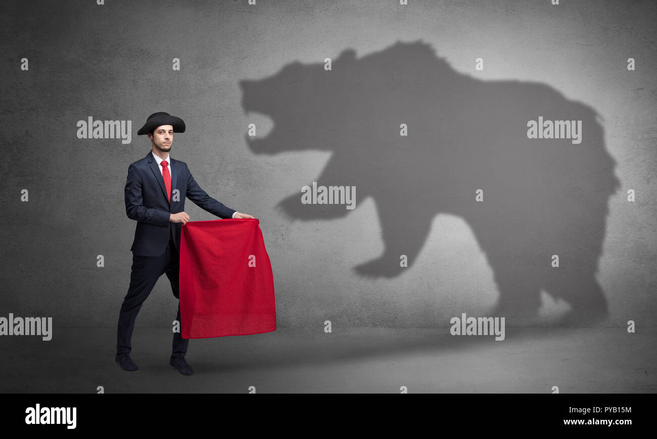 Businessman standing with red cloth in his hand and big bear shadow on ...