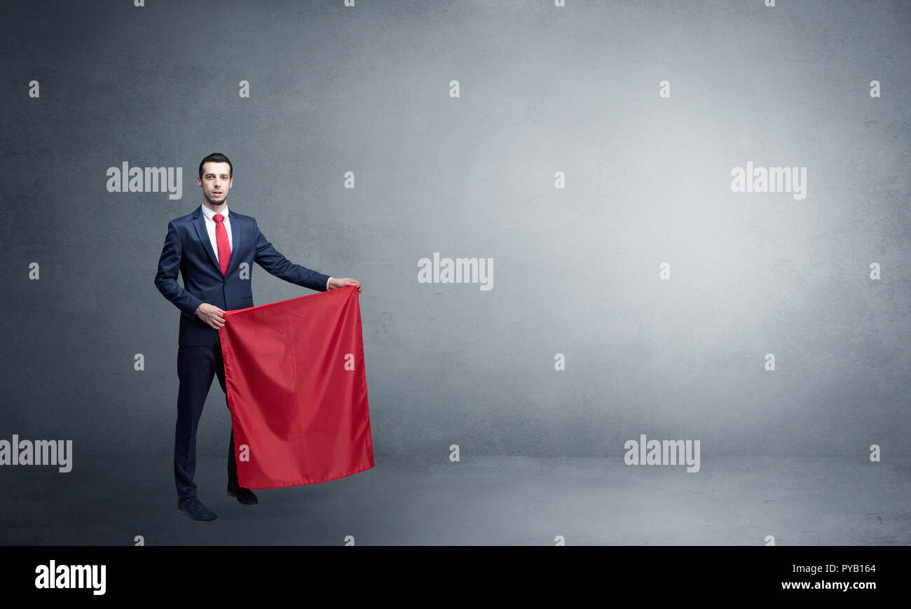 Businessman standing with red toreador cloth in his hand in an empty ...