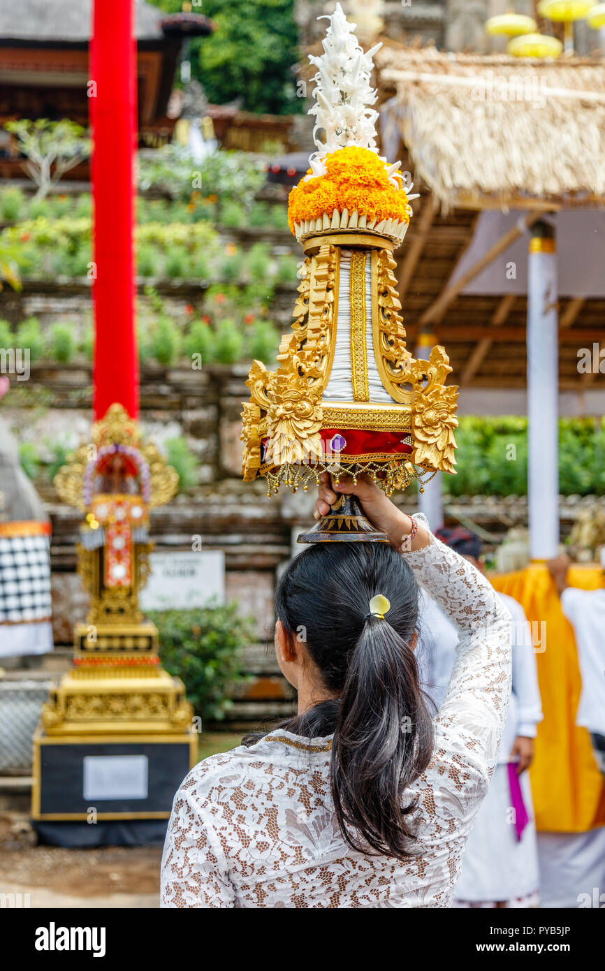 Balinese girl in kebaya and sarong with banten tegeh (tall offerings ...