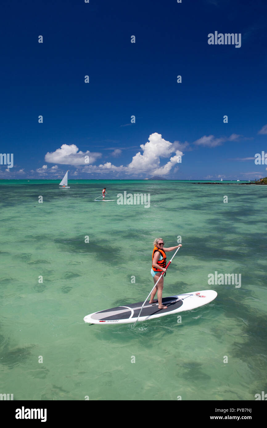 Tourist stand up paddle boarding on the north coast of Mauritius Stock ...