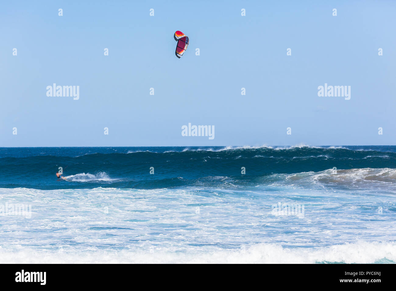 Kite surfer surfing wind flying ocean wave launch high into blue sky ...