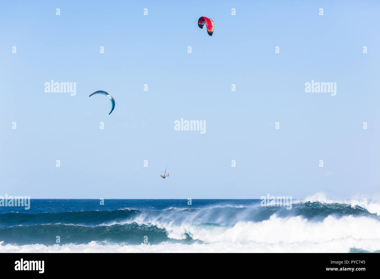 Kite surfer surfing wind flying ocean wave launch high into blue sky ...