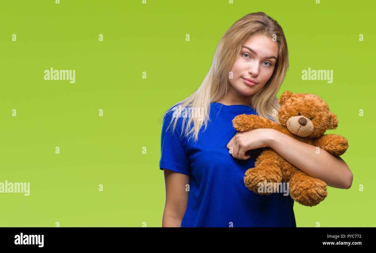 Young caucasian woman holding cute teddy bear over isolated background ...