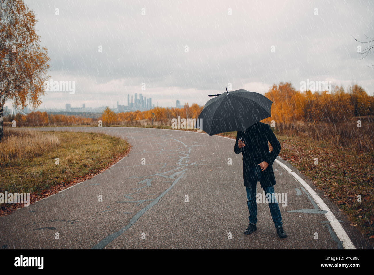Young man in black coat walking in the rain with umbrella Stock Photo ...