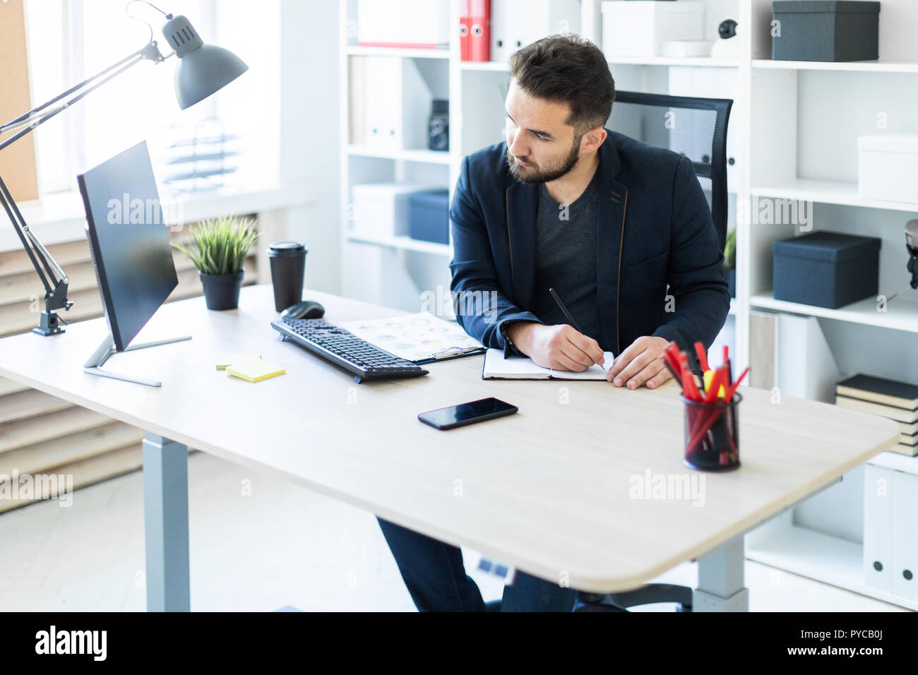 The young man works in the office at a computer Desk with documents ...