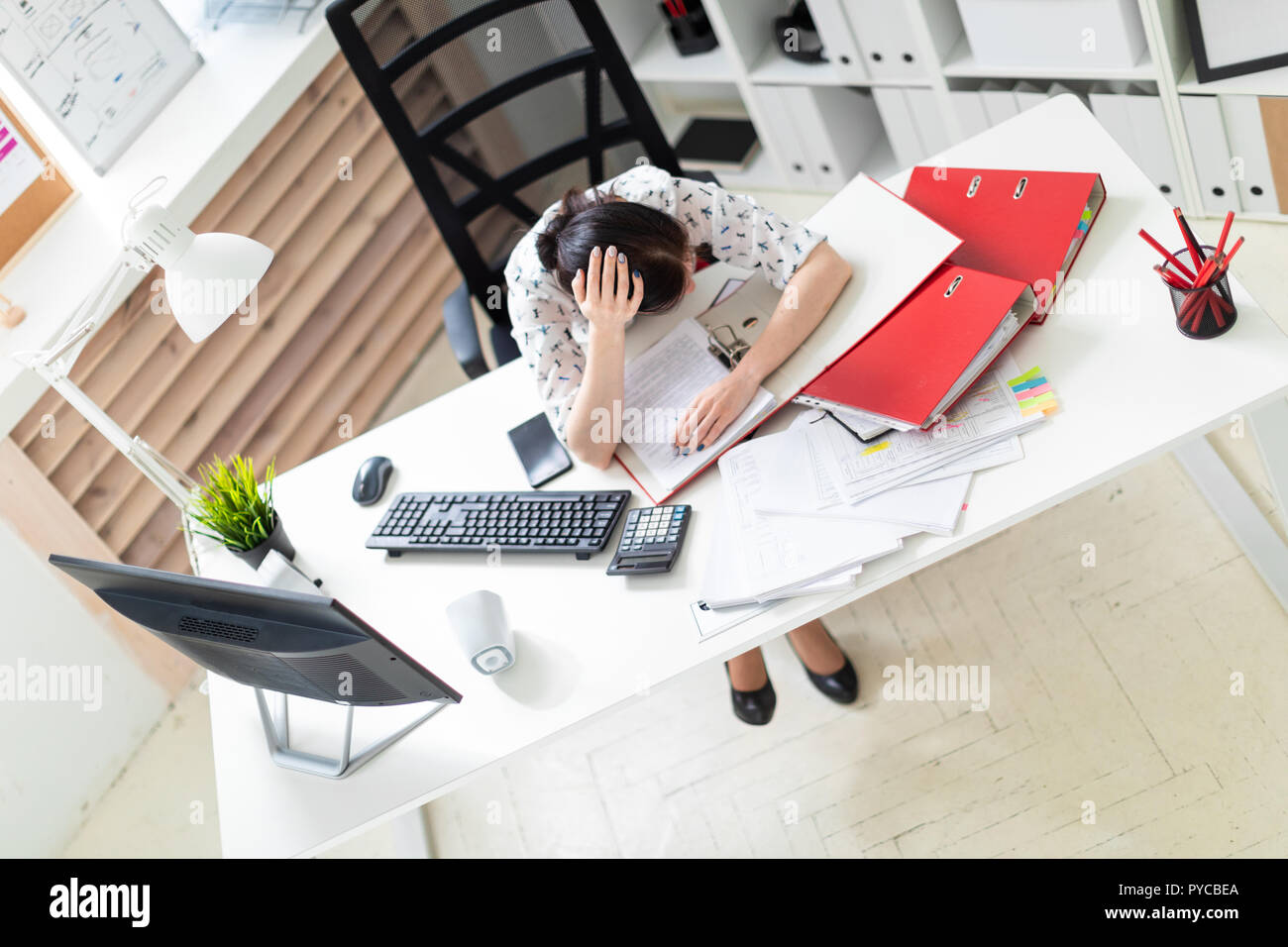 A young girl sitting in an office chair at a computer table and put her ...
