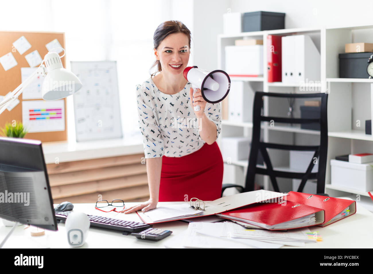 A young girl stands in the office near the table and says in a shout ...