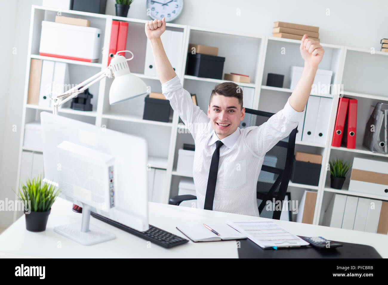 A young man sitting at a computer Desk in the office and raised his ...