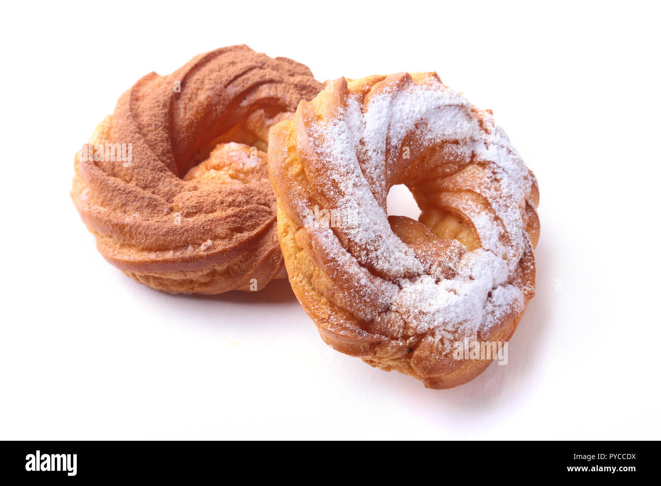 Chocolate and powdered sugar cream puff rings, choux pastry. Isolated ...
