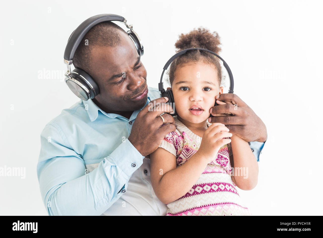 Cute little girl and her dad are listening to music with headphones on ...
