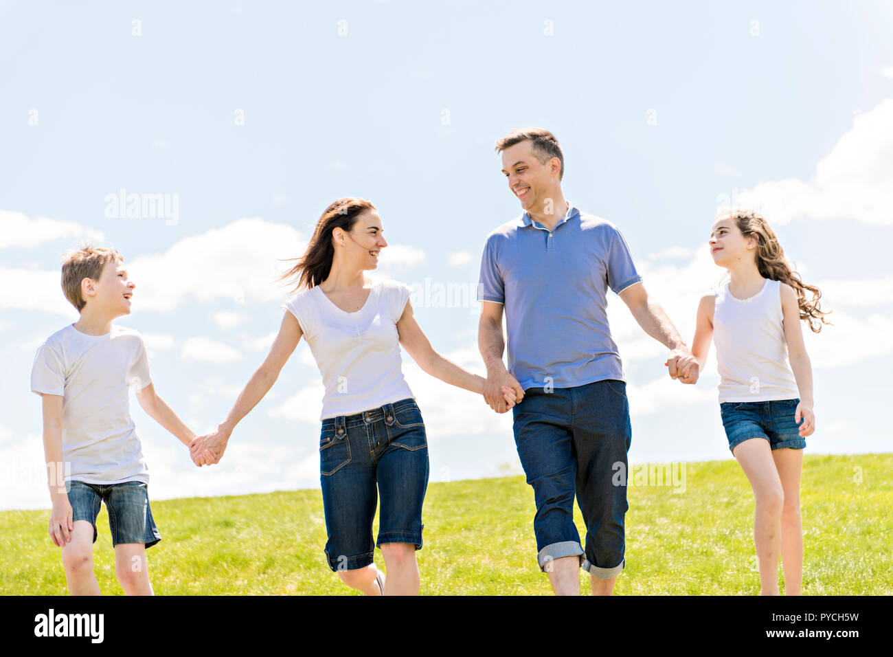 Family of four outdoors in a field having fun Stock Photo - Alamy