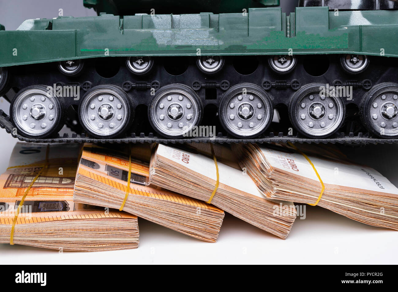 Close up green tank toy placed on euro banknotes pile. business and ...