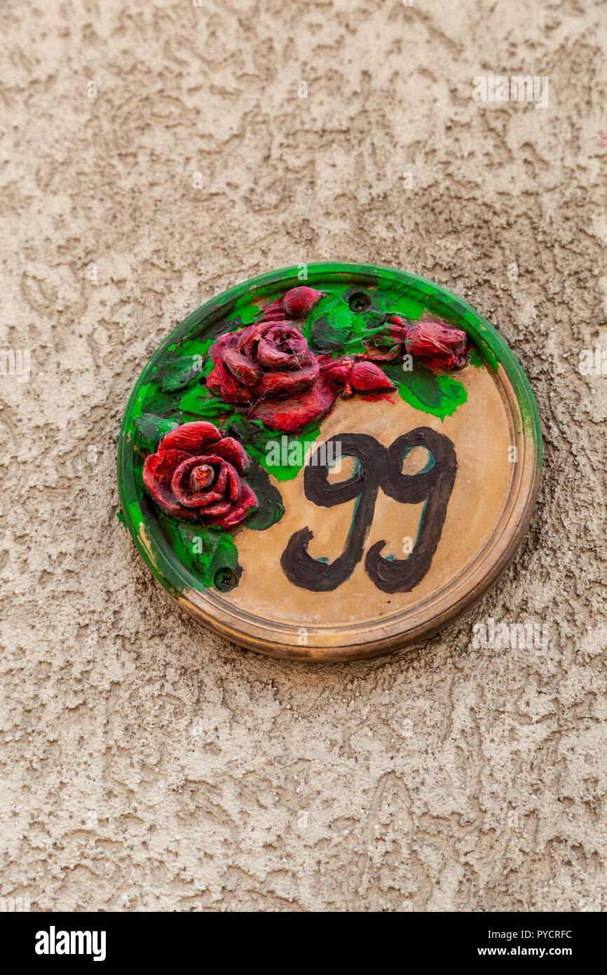 House number ninty-nine 99 on circle plaque with red roses green leaved ...