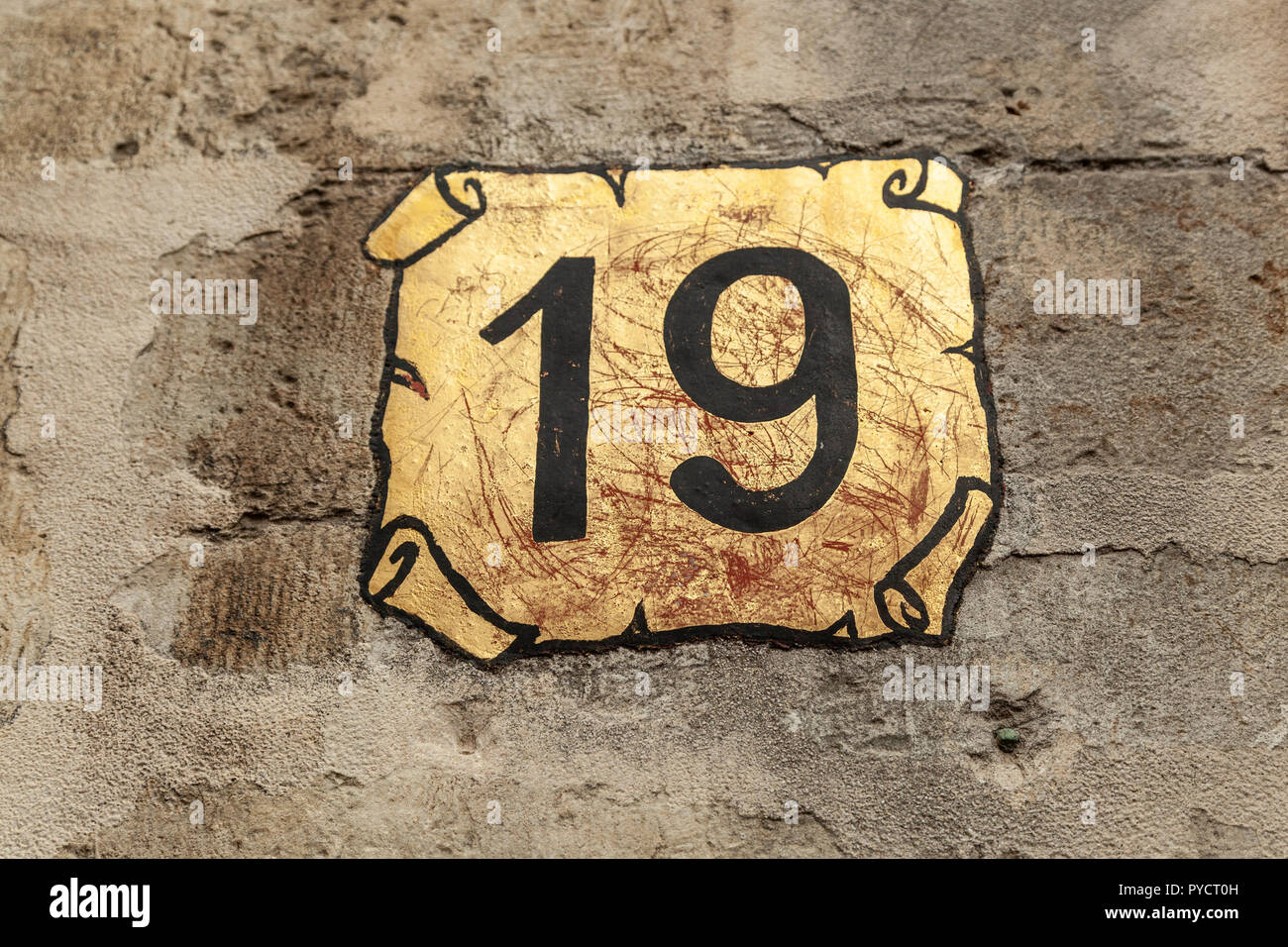 House number nineteen 19 painted black on gold in a square scroll ...