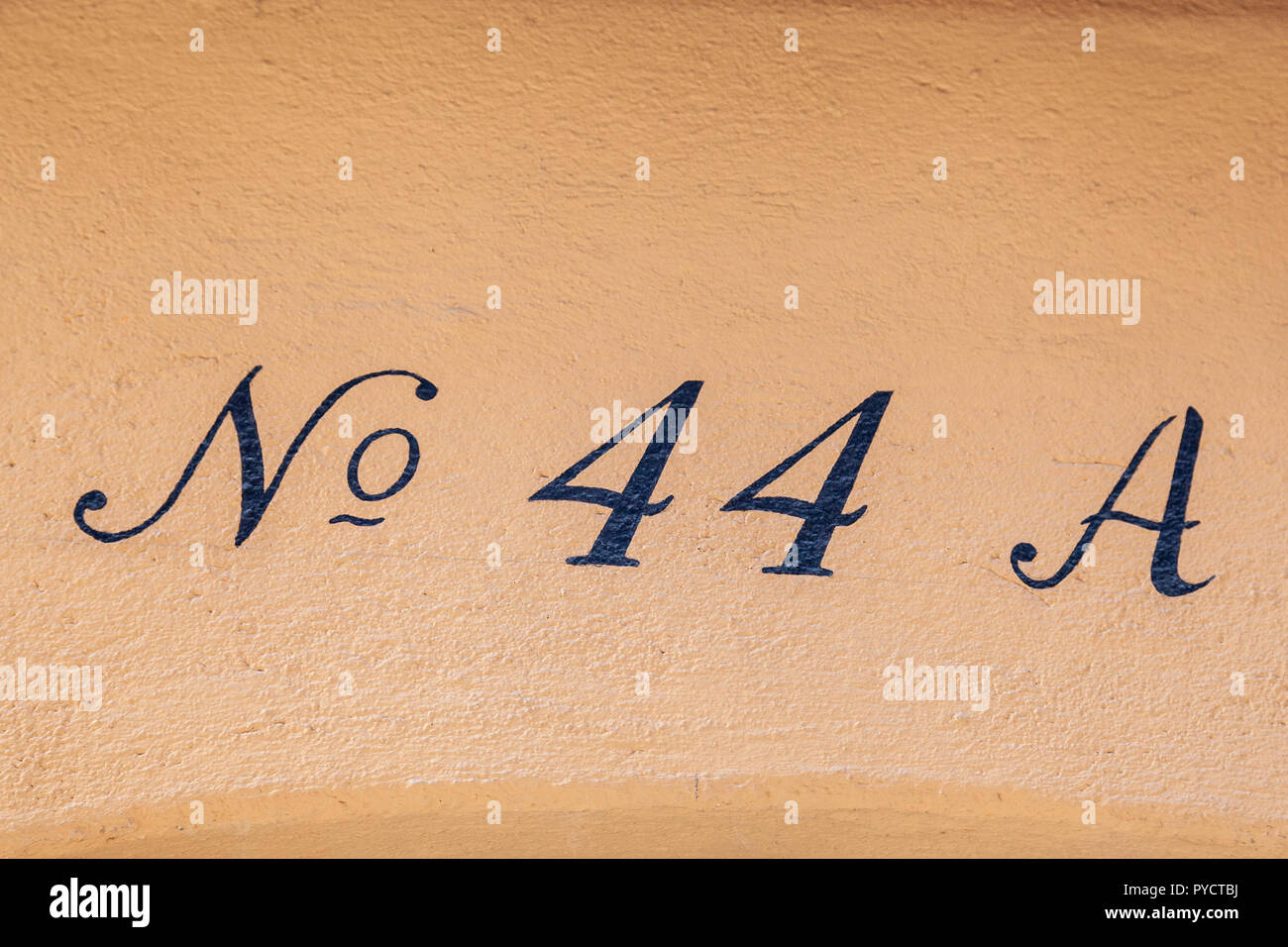 House number fourty-four A 44A painted black on yellow render in ...
