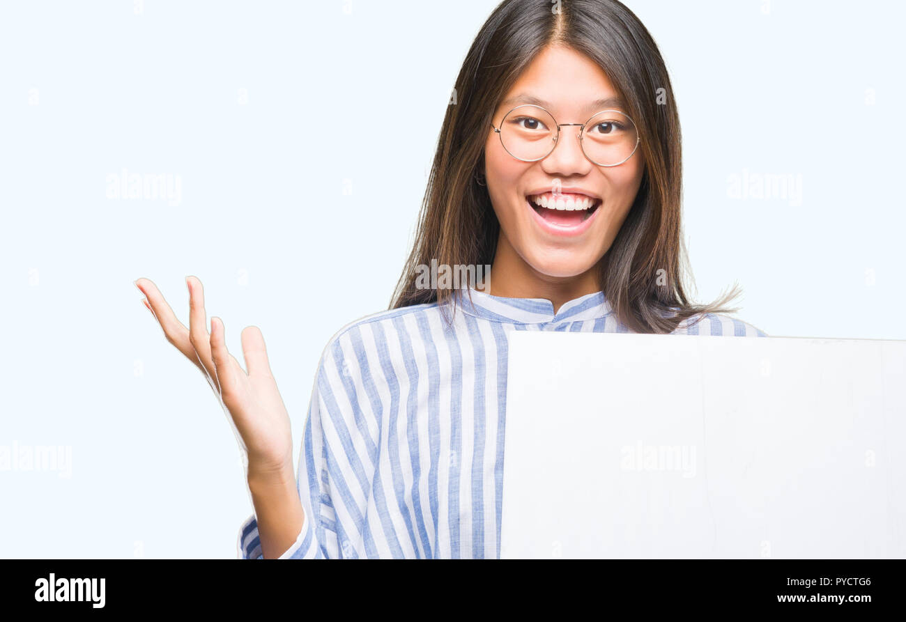Young asian woman over isolated background holding blank banner very ...