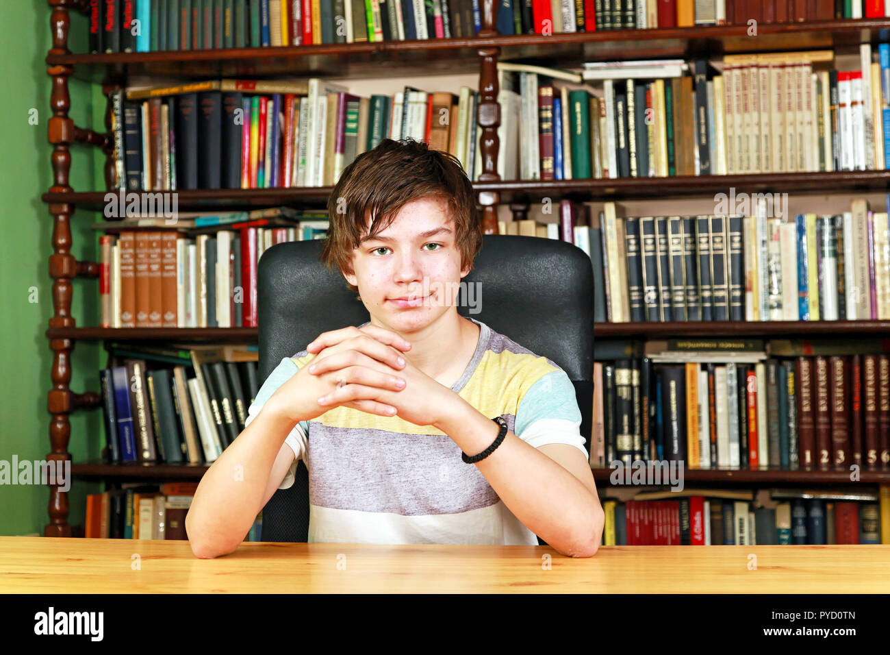 Teenage boy sitting in school library and bored up Stock Photo - Alamy