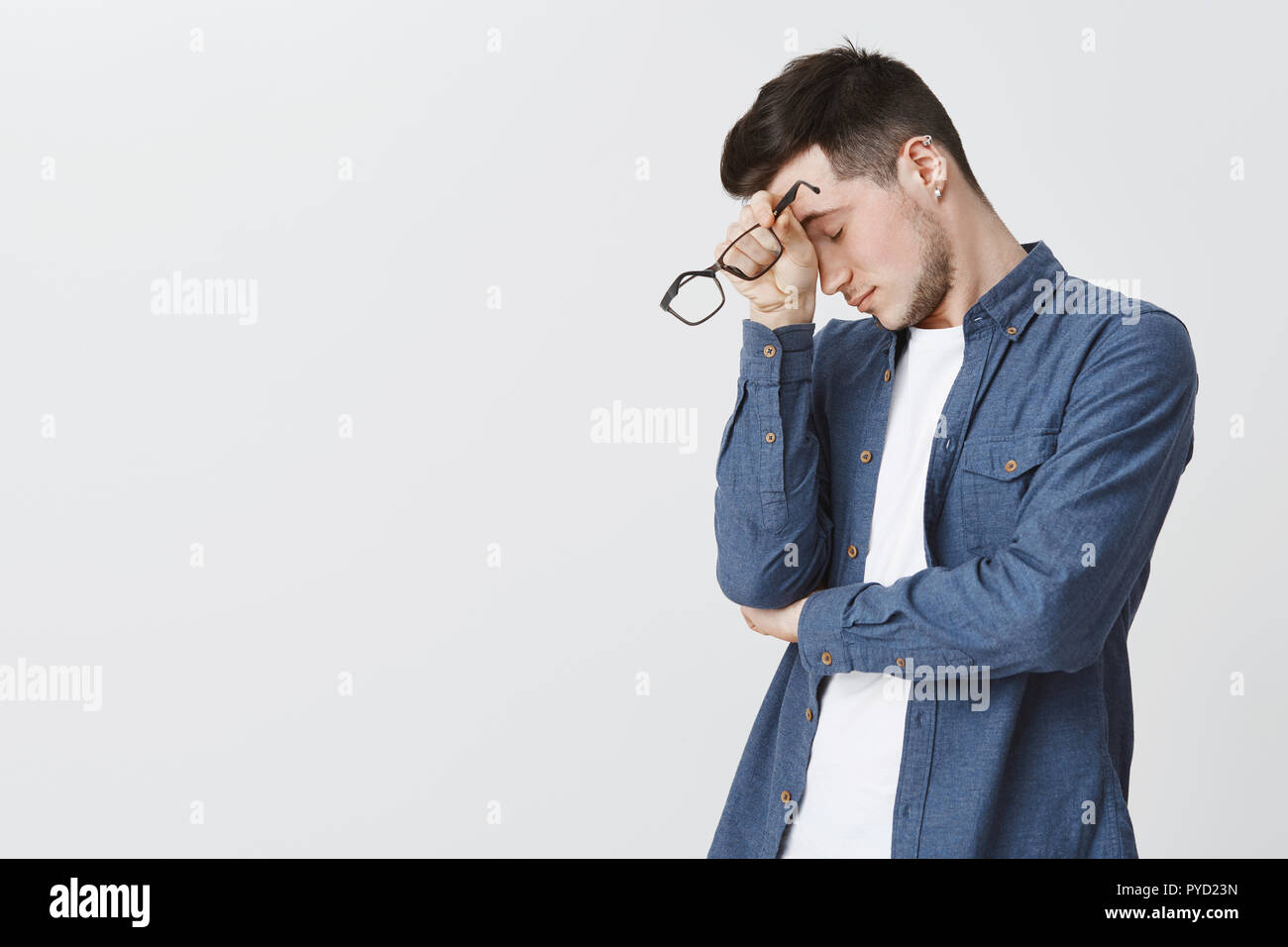 Attractive young male model with bristle and pierced ear turning left ...