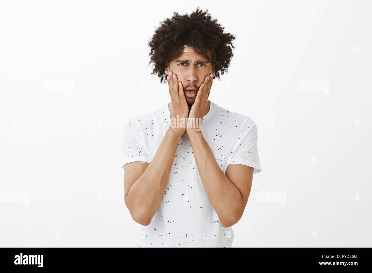 Gloomy good-looking dark-skinned man with curly hair holding palms on ...