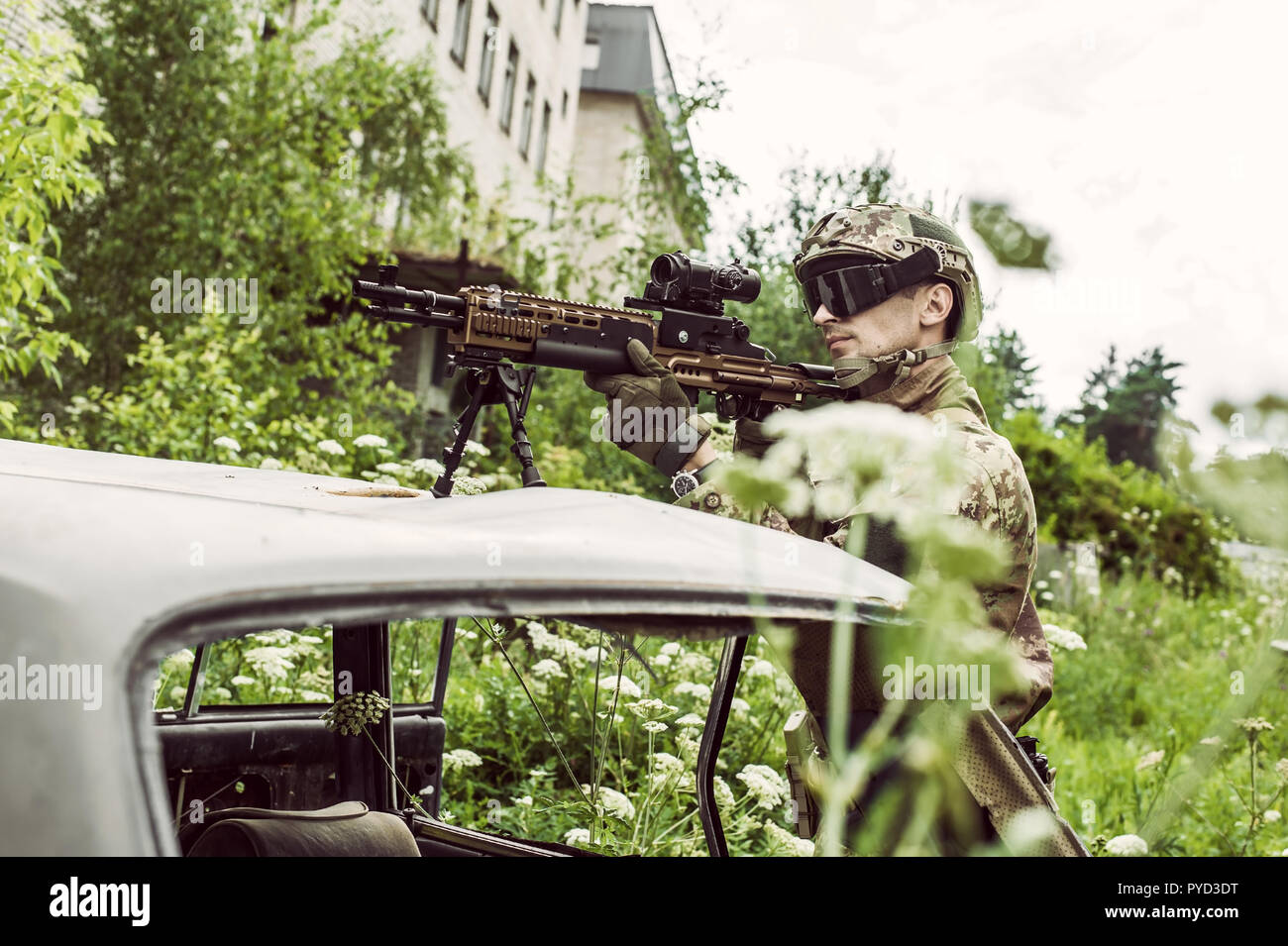 Military man sniper with automatic rifle aims into the distancefrom ...