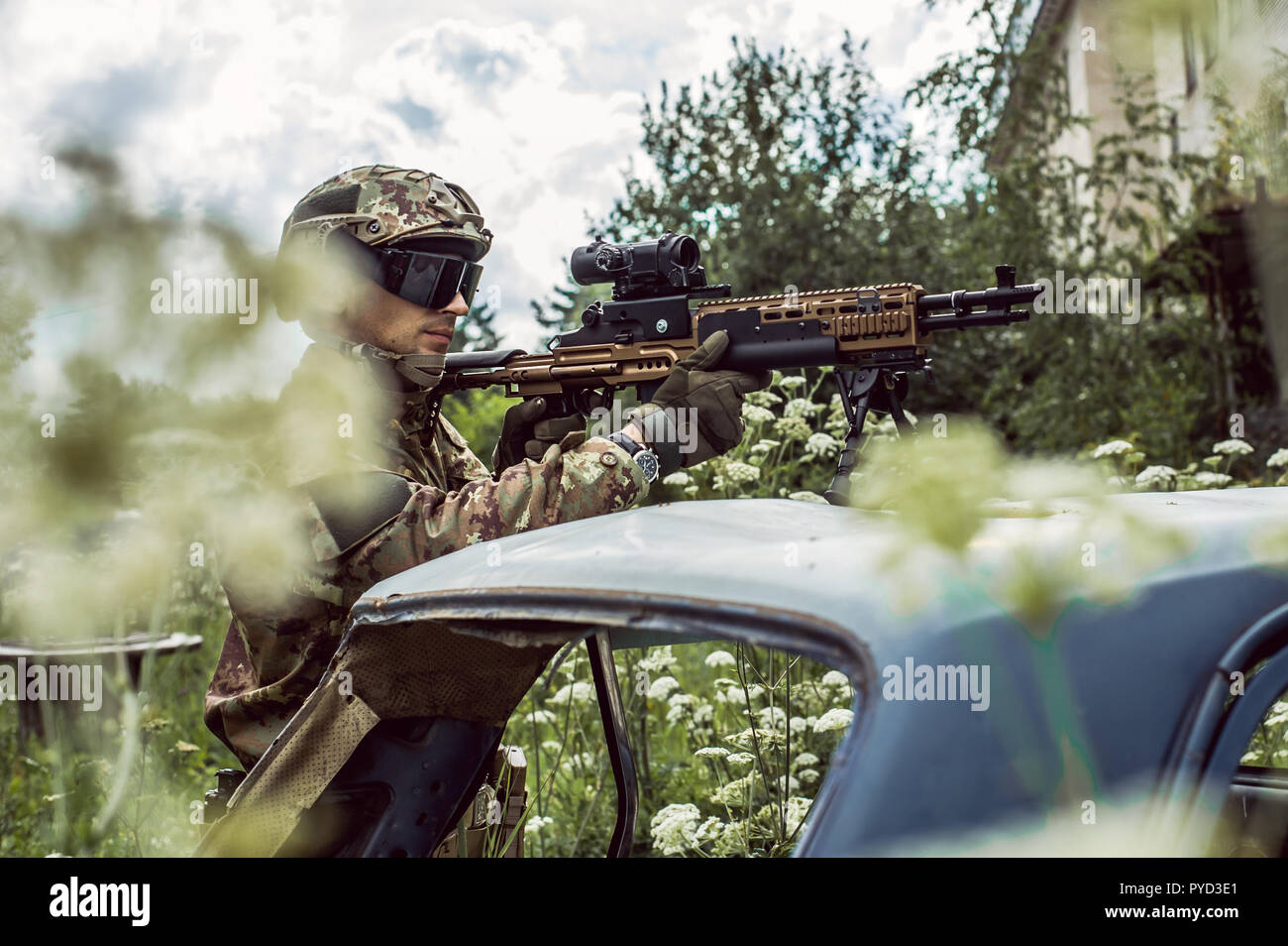 Military man sniper with automatic rifle aims into the distancefrom ...