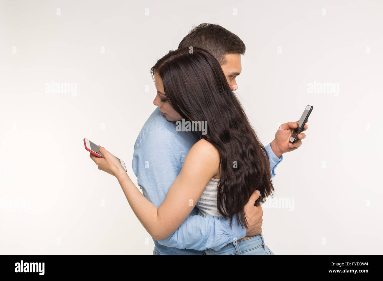 Smartphone addiction concept - young couple hugging and typing on their ...