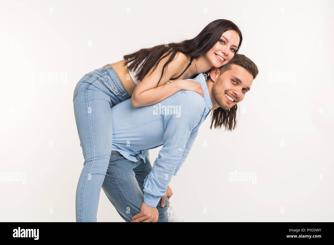 Young male carrying his girlfriend piggyback. They are fooling around ...