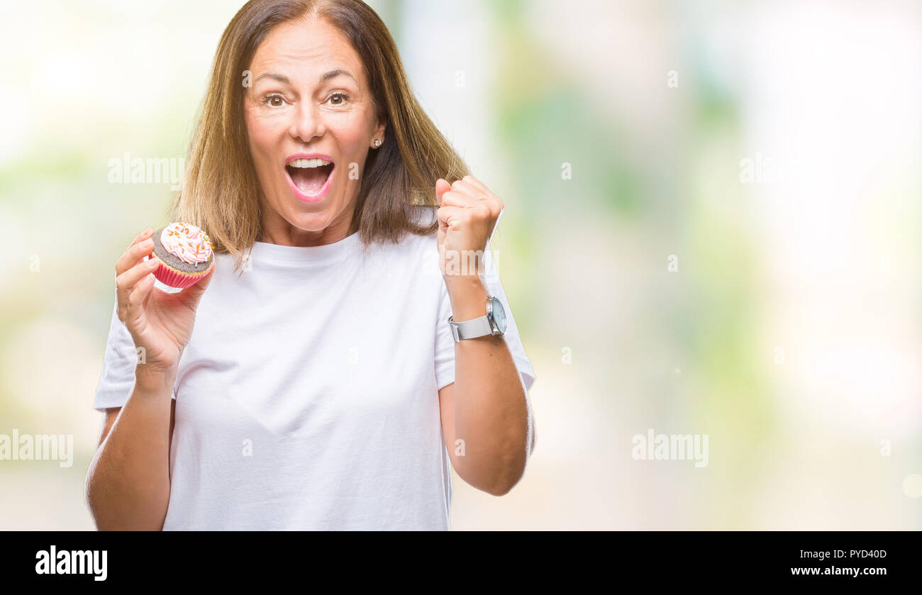 Middle age hispanic woman eating cupcake over isolated background ...