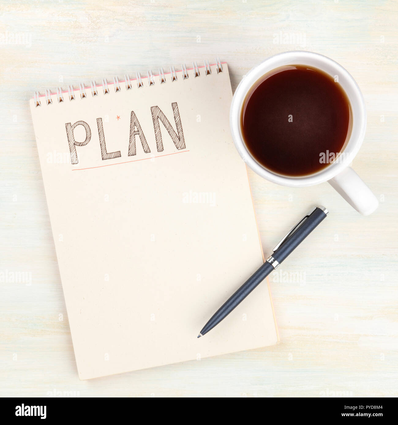 A photo of a spiral notepad with the word Plan, with a cup of coffee ...