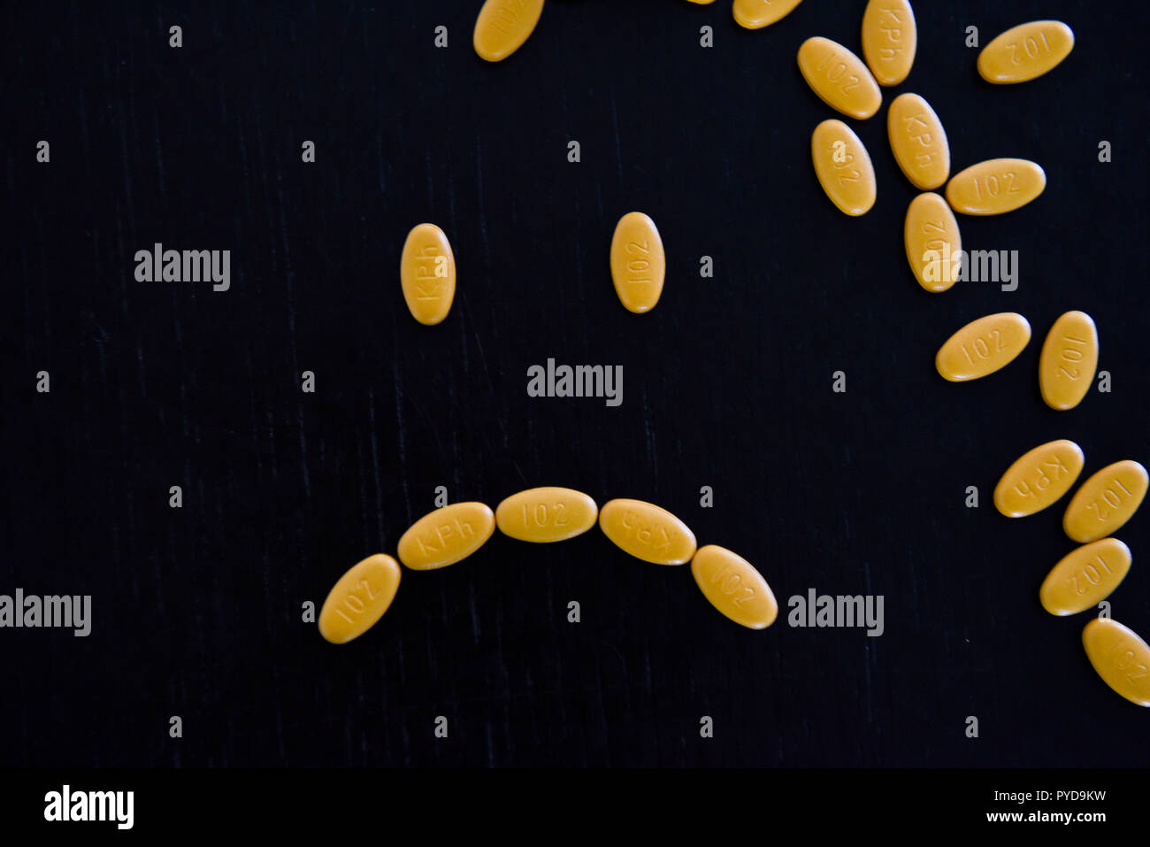 Sad smiley made with yellow pills on the black table Stock Photo - Alamy