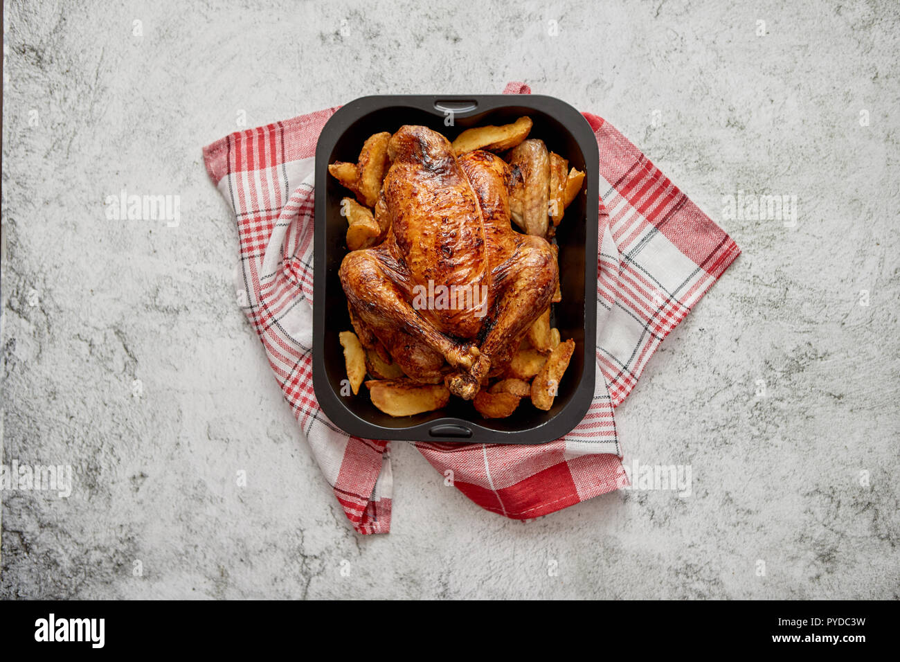 Roasted chicken or turkey with potatoes in black steel mold placed on ...