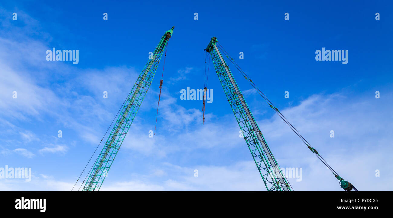 crane boom arms or booms outlined against a blue sky Stock Photo - Alamy