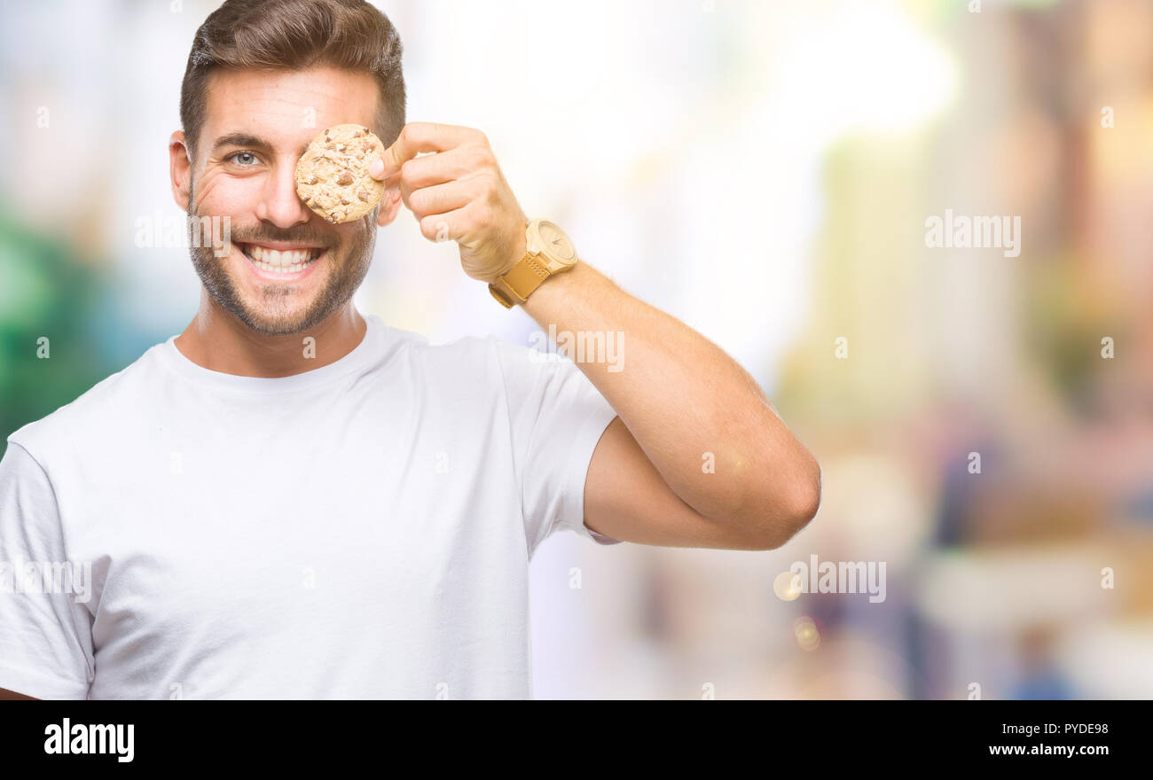 Young handsome man eating chocolate chips cookie over isolated ...