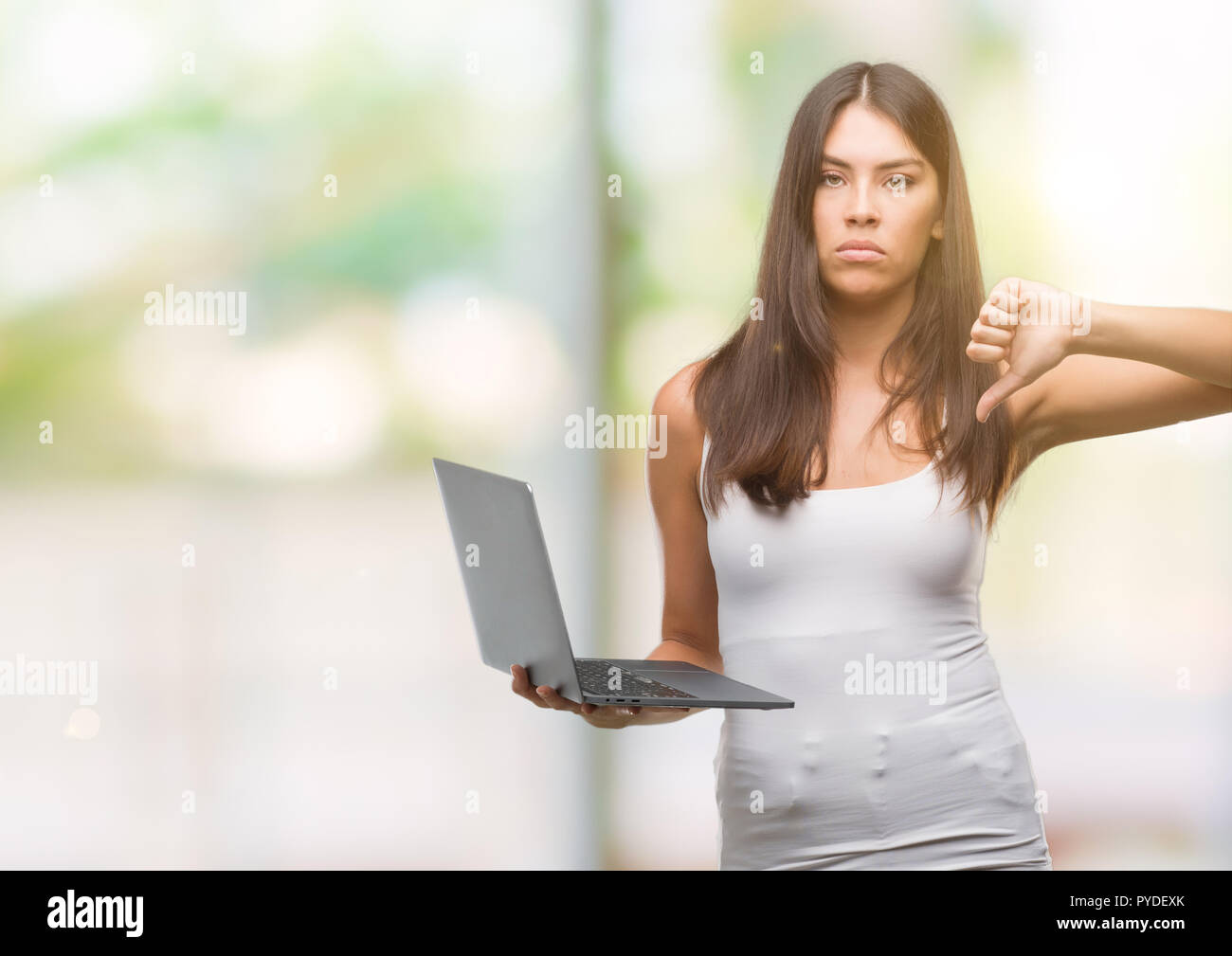 Young hispanic woman using computer laptop with angry face, negative ...