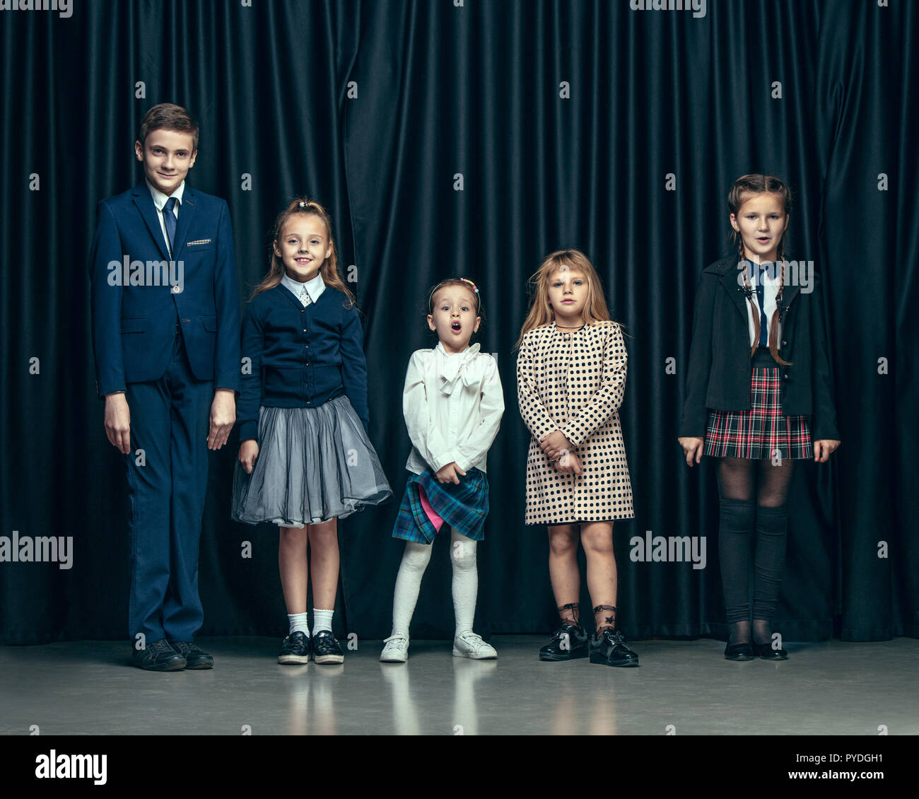 Cute surprised stylish children on dark background. Beautiful stylish teen girls and boy ...