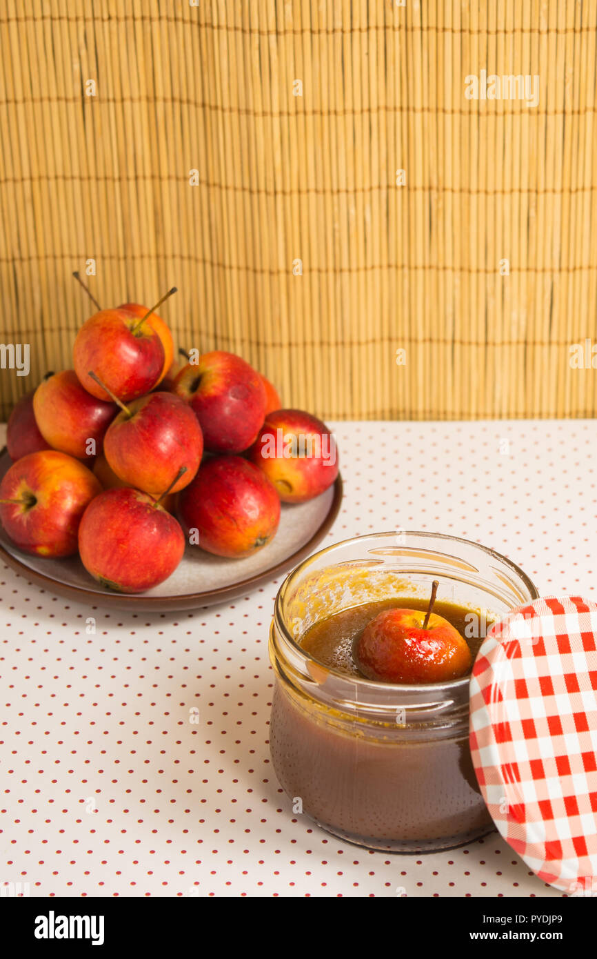 Fresh mini apples with jar of caramel on the table and the straw ...