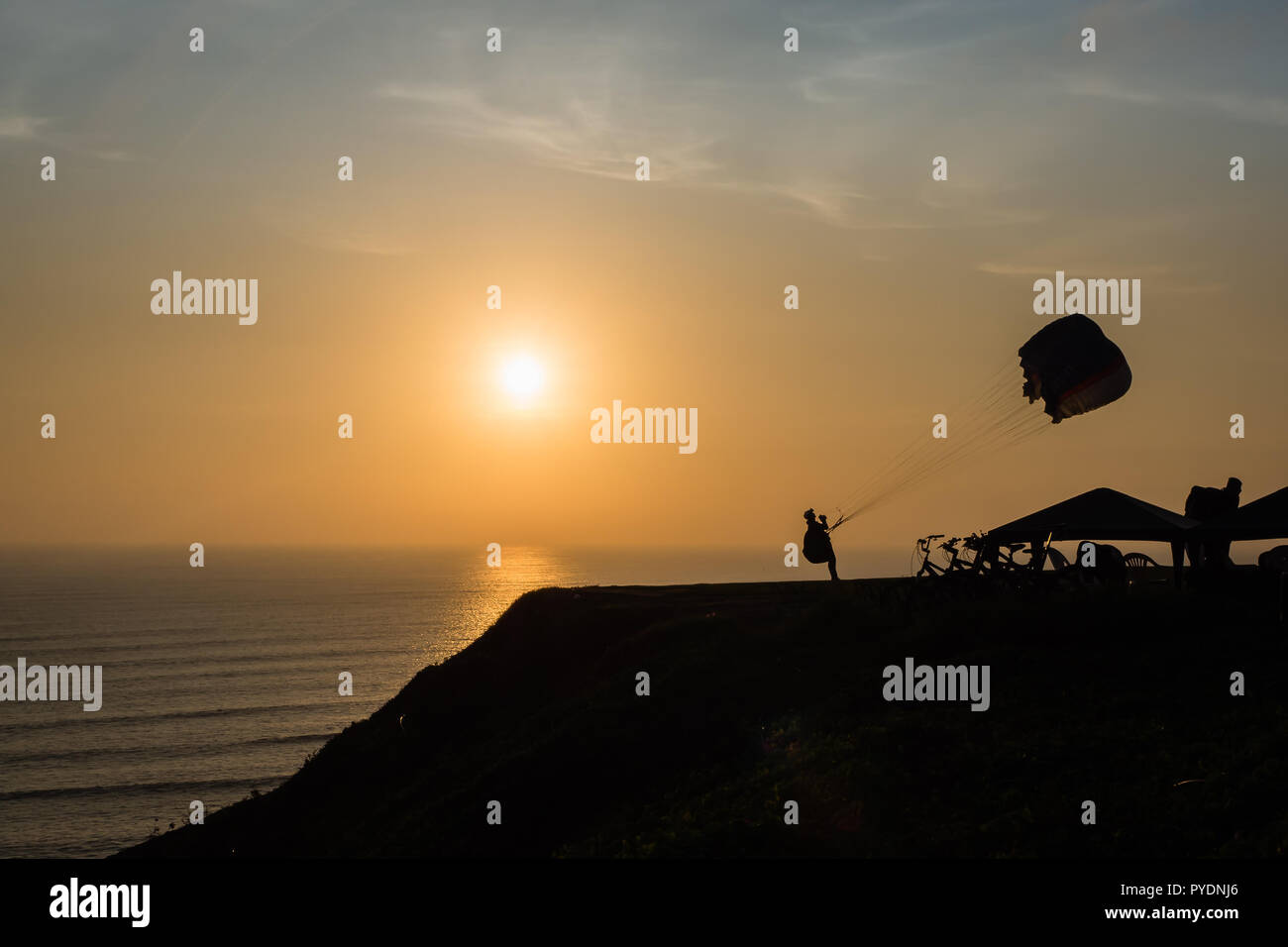 Sunset in the cliffs of Lima city in Peru, with a man doing paragliding ...