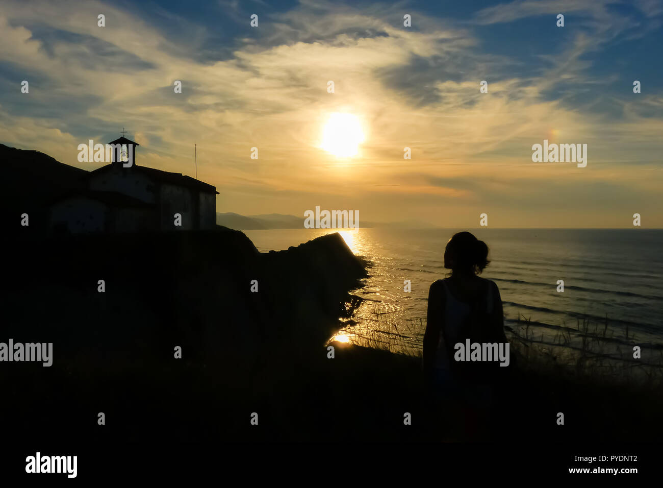 Sunset in the coast with church and woman silhouette. Basque Country ...
