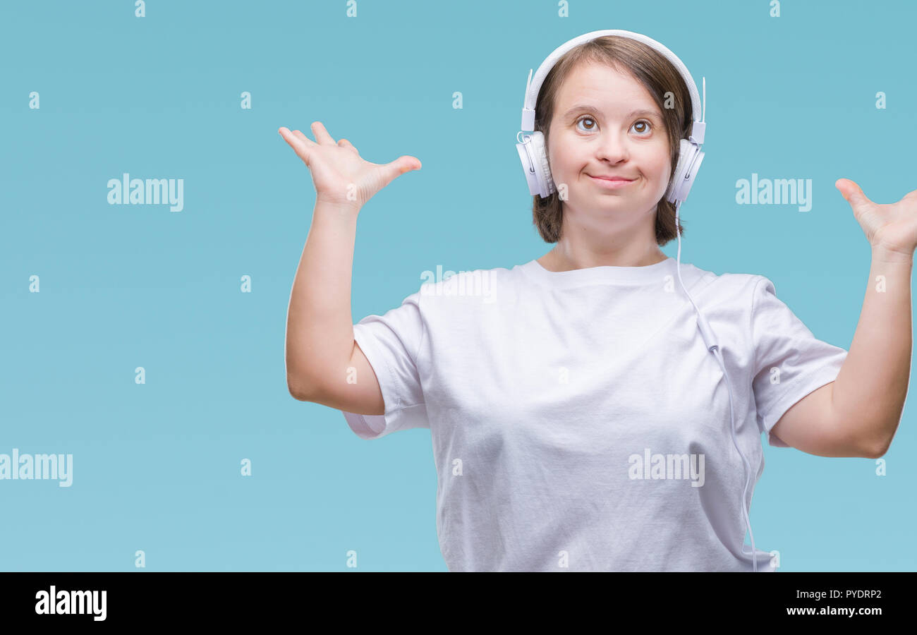 Young adult woman with down syndrome wearing headphones over isolated ...