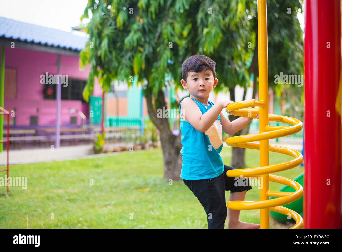 Active Asian Kid playing climbing metal spiral at school yard ...