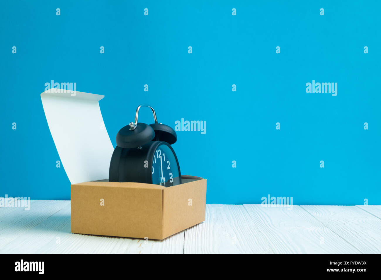 Retro alarm clock in brown delivery cardboard box or tray on white wood ...