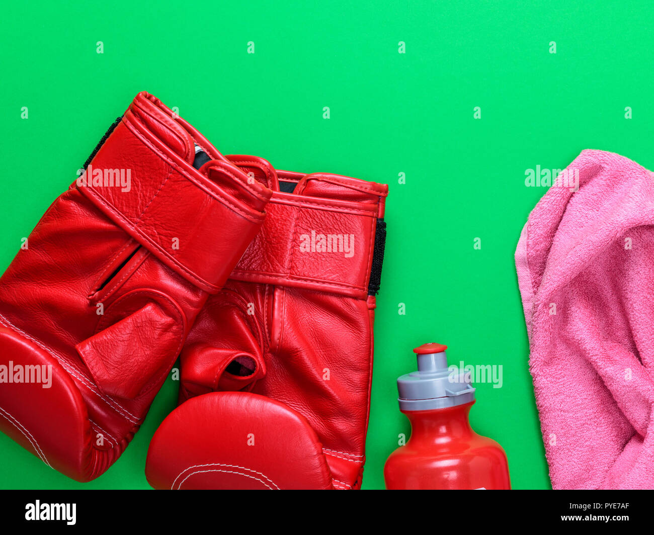 red leather boxing gloves, a plastic water bottle and a pink towel on a ...