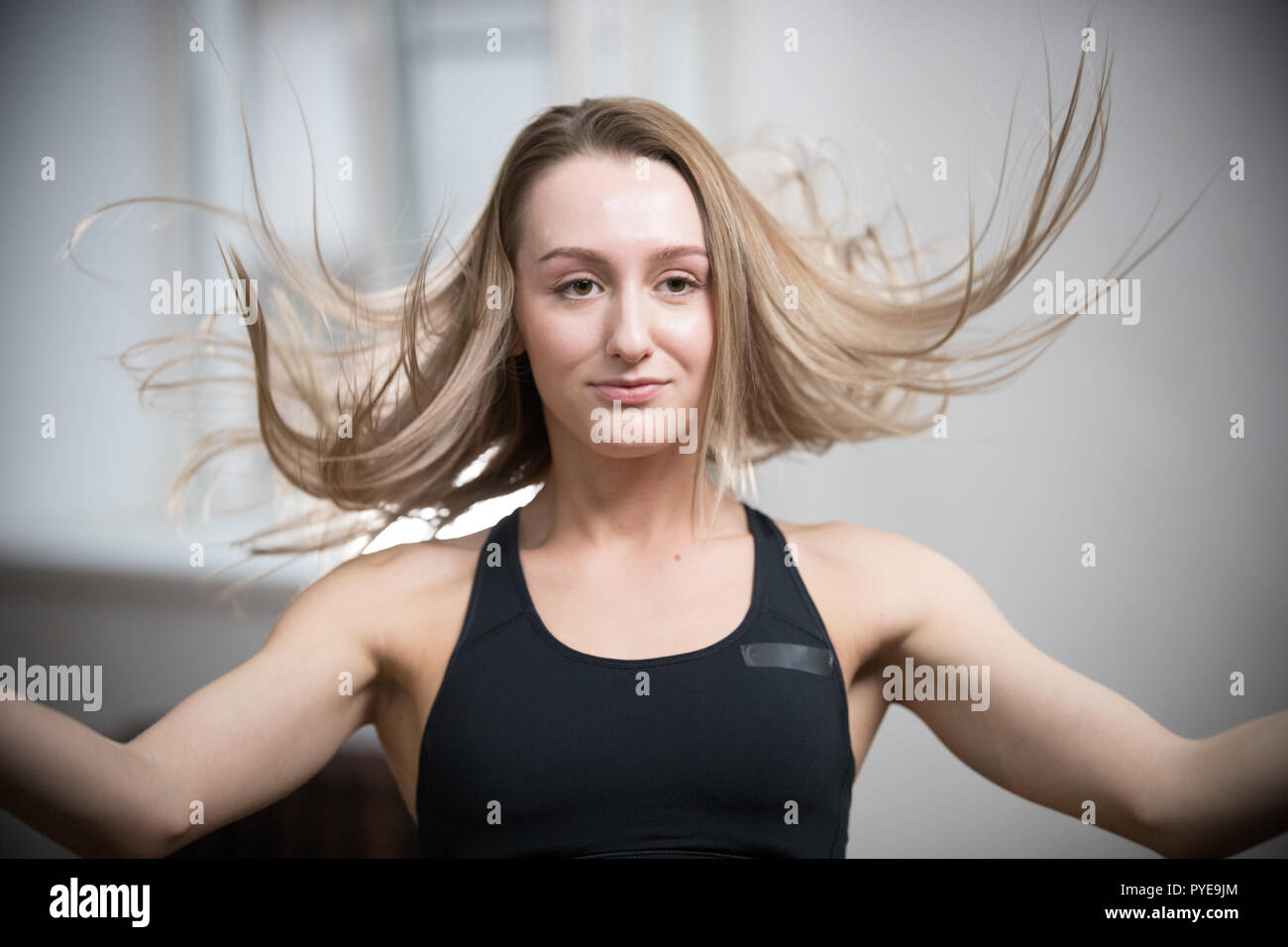 Young attractive woman in sport bra in training studio. Flying hair ...