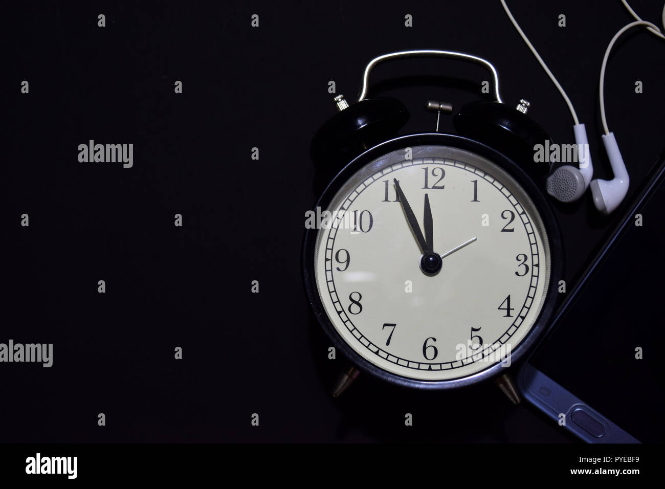 black vintage alarm clock on the black background Stock Photo - Alamy