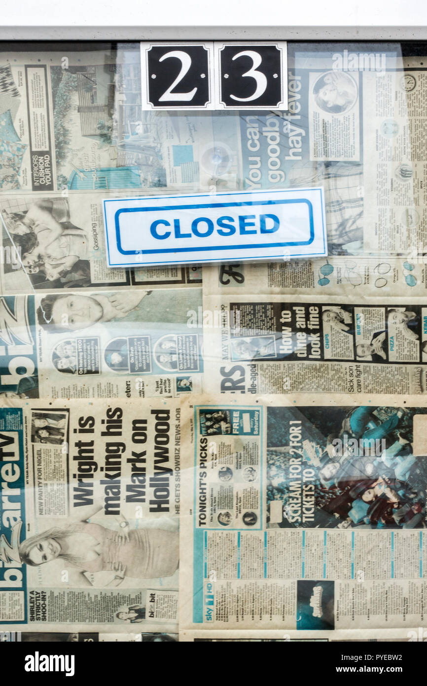 Faded newspapers behind the window of a shop door with the number 23 at ...