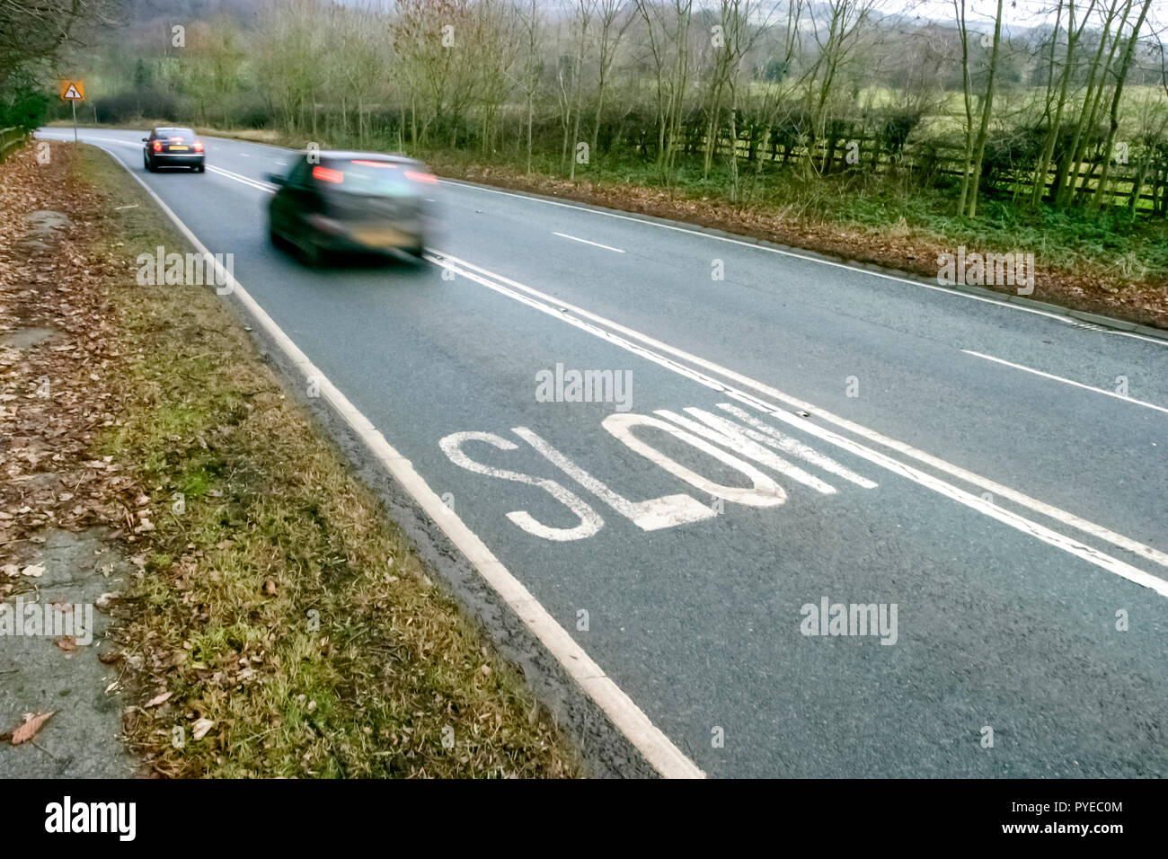 Traffic, cars and lorry, driving along a country road with Slow marked ...