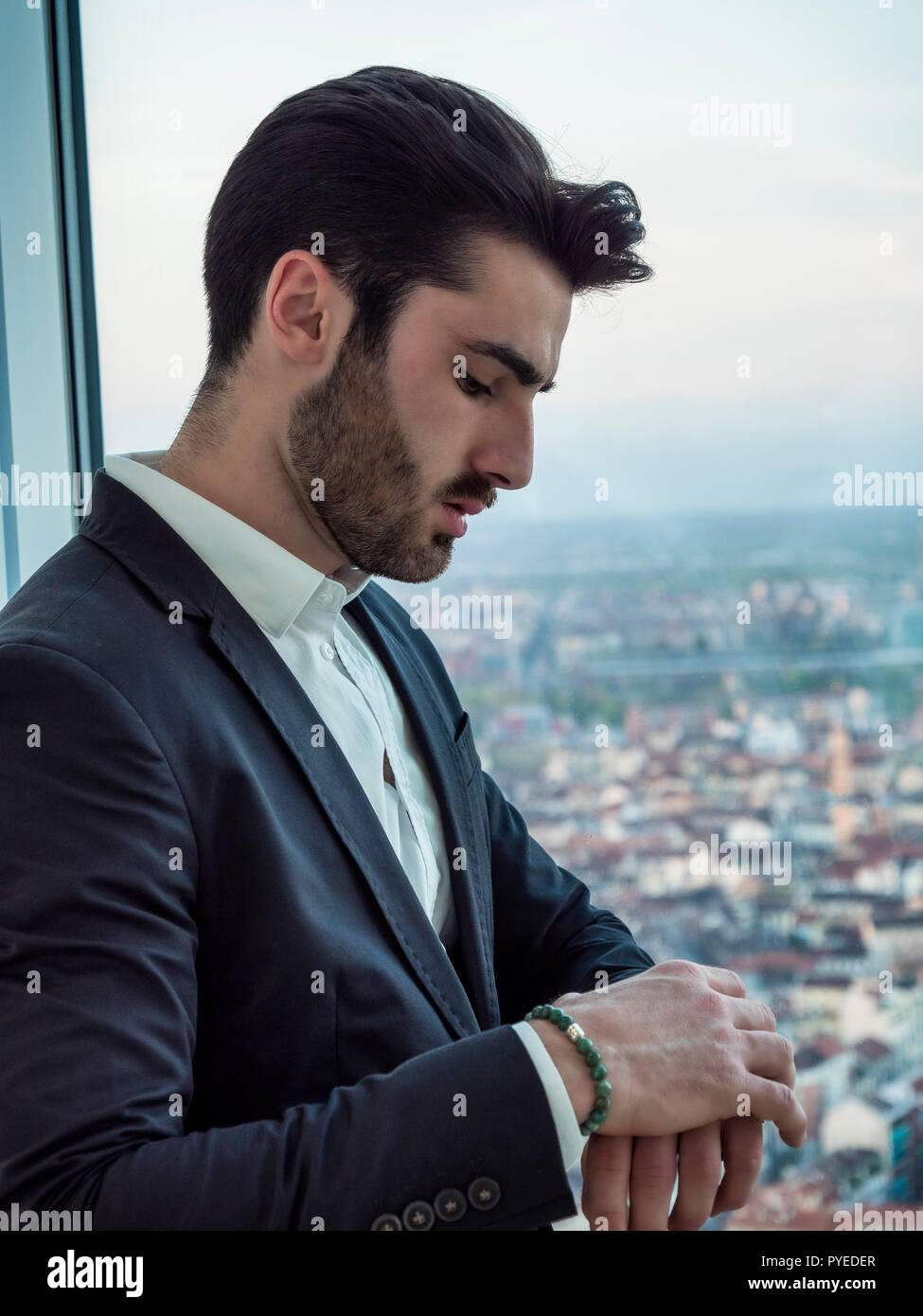 Portrait of stylish young man wearing business suit, standing in modern ...