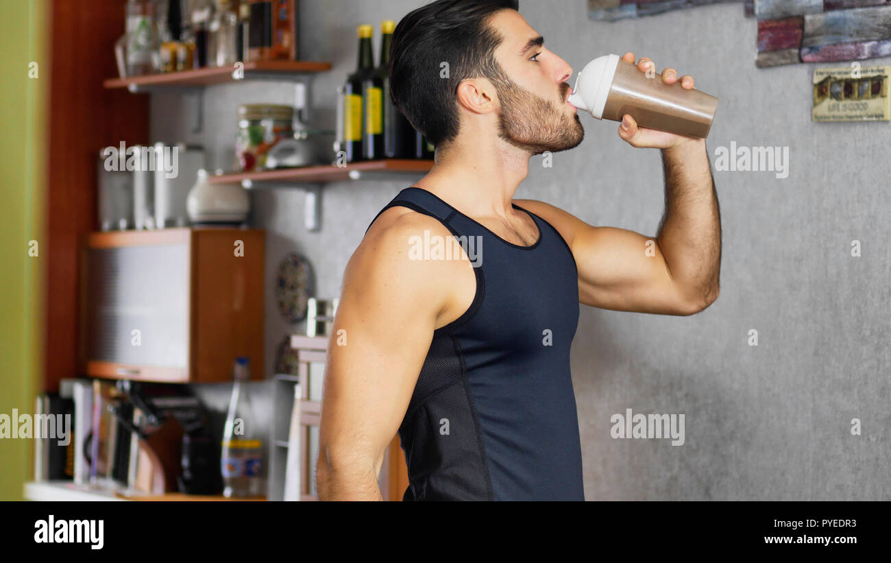 Young athletic man drinking a healthy smoothie drink or a protein shake ...